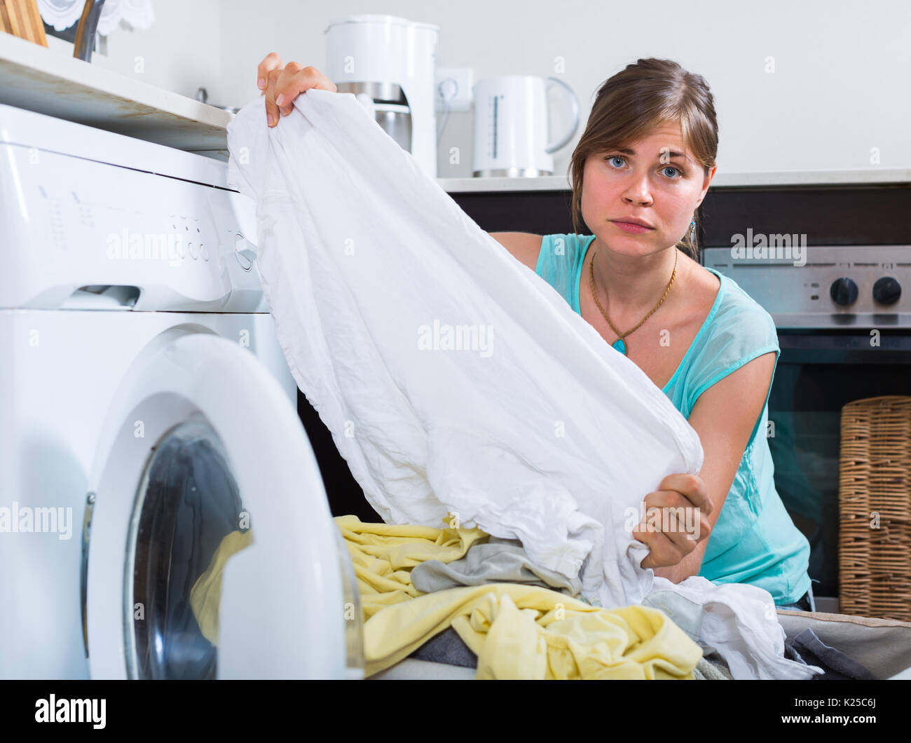 Upset maid looking at clothes with persistent stains after laundry ...