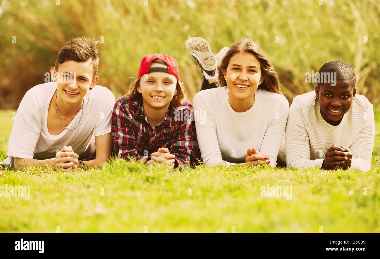 Group of joyful smiling teenage friends having fun outdoors lying on ...