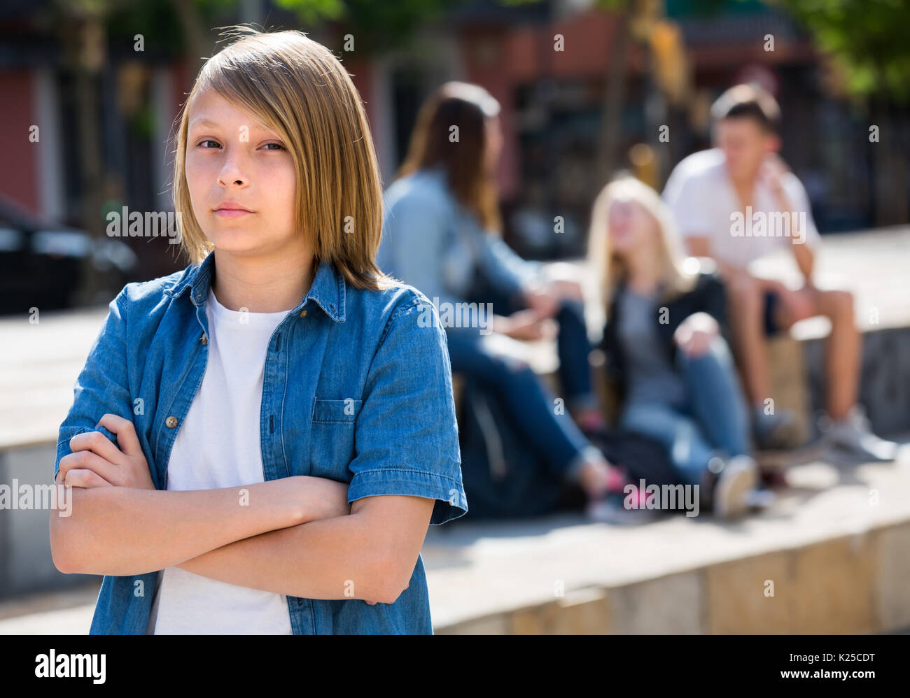Portrait of outcasted teenager boy being mobbed by other teenagers ...