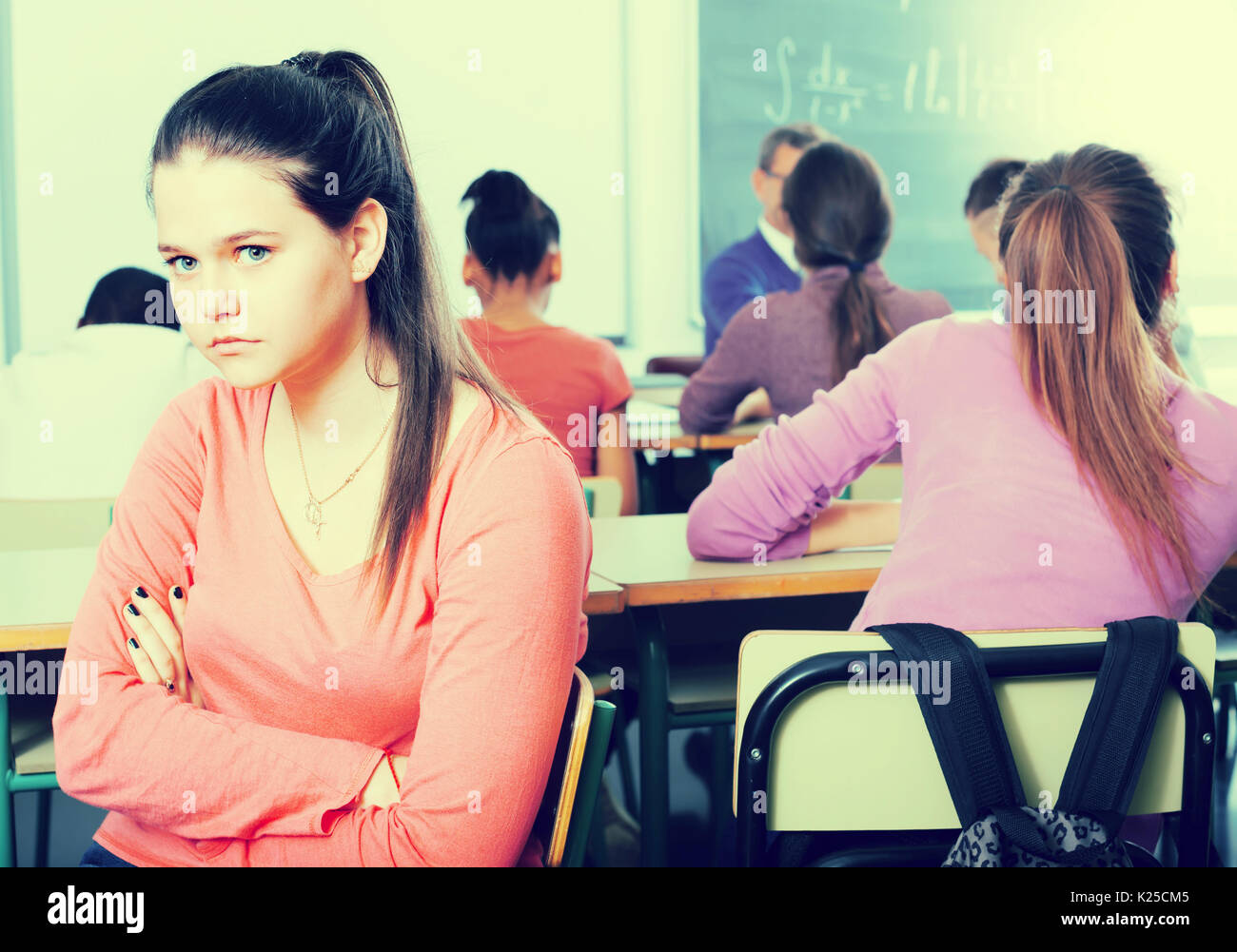 portrait of a sad student sitting lonely while others listening the ...