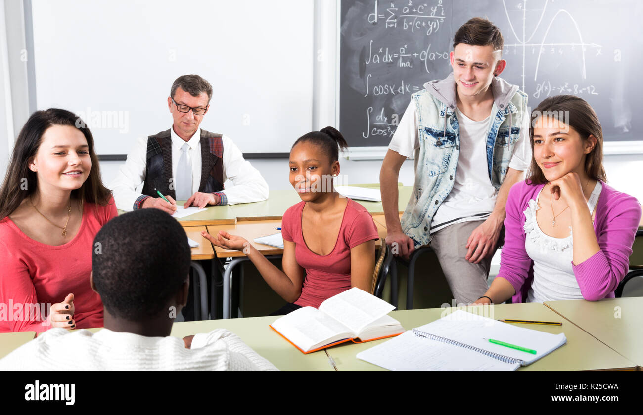 Happy students of different nationalities sitting and talking in the ...