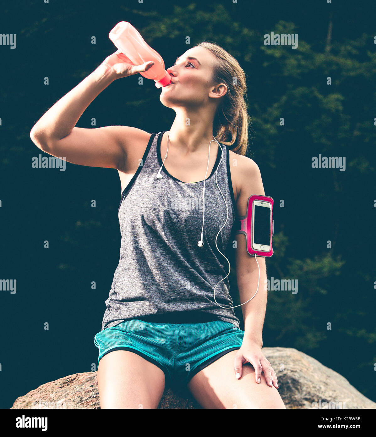 Beautiful fitness woman drinks while running outdoors Stock Photo - Alamy