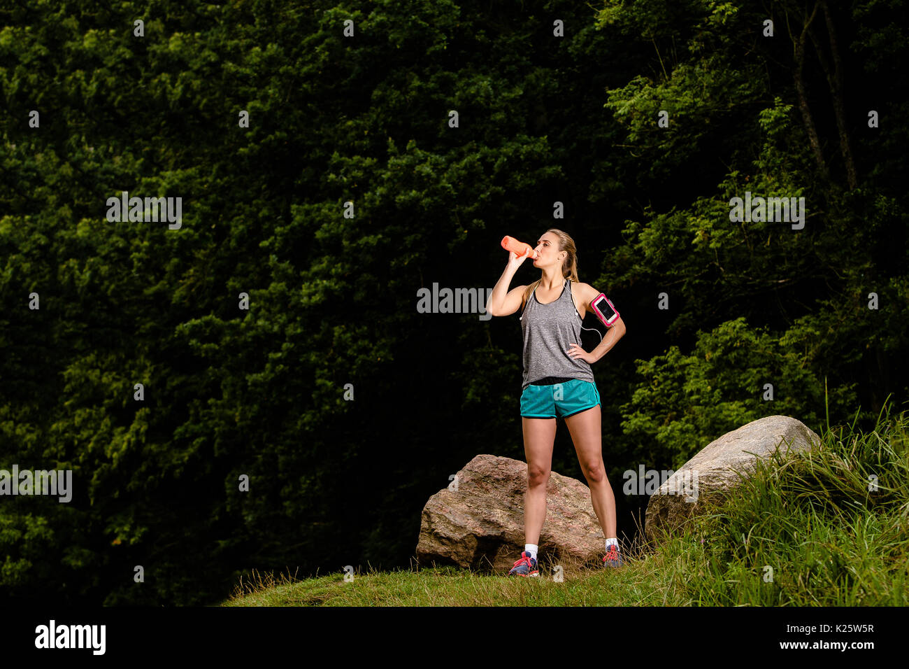 Beautiful fitness woman drinks while running outdoors Stock Photo - Alamy
