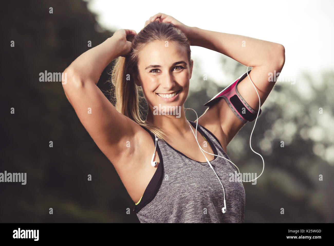 Beautiful fitness woman tying hair while running outdoors Stock Photo ...