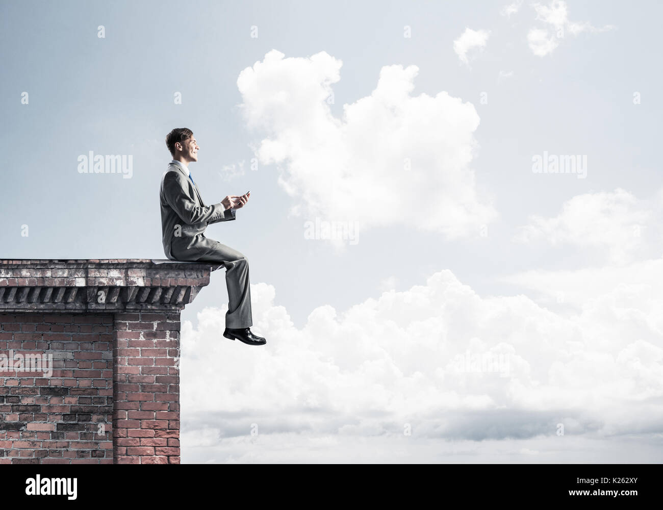 Man on roof edge reading book and cityscape at background Stock Photo ...