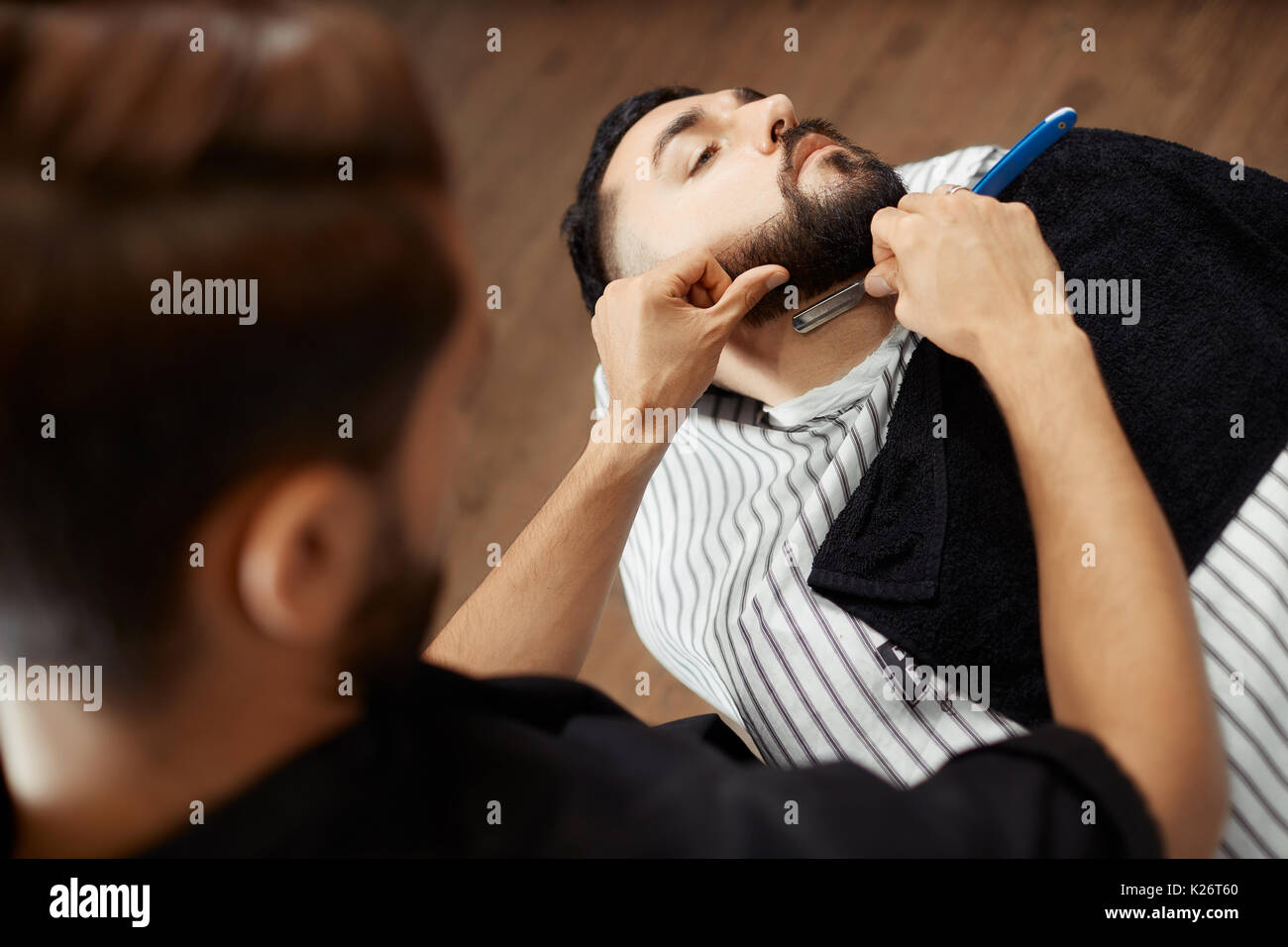 Professional hairdresser cutting bread for brunet man in barber shop ...