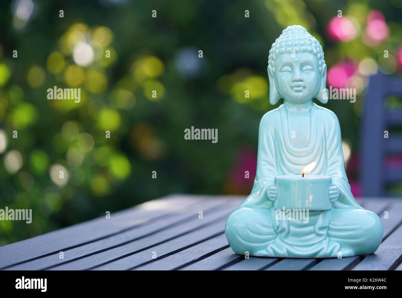 Aqua blue Buddha statue in colorful garden setting Stock Photo - Alamy