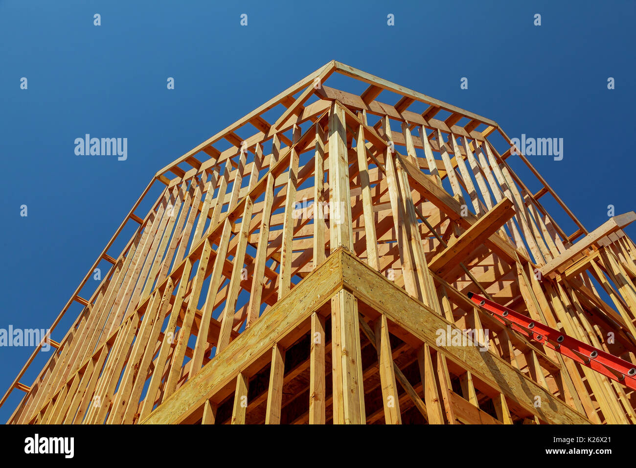 New residential construction home framing against a blue sky and sun ...