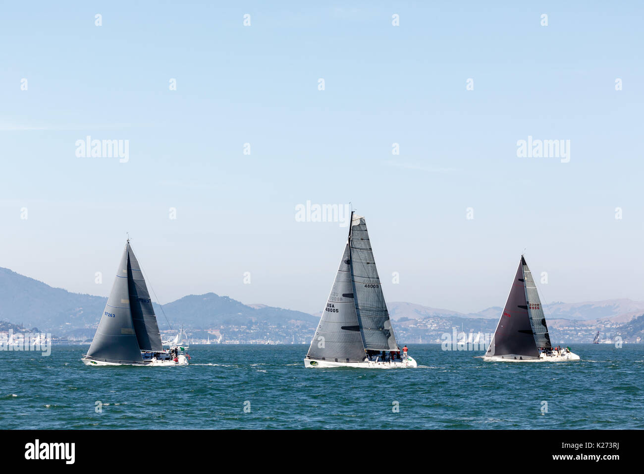 three sailboats follow each other toward the buoy in a race Stock Photo ...