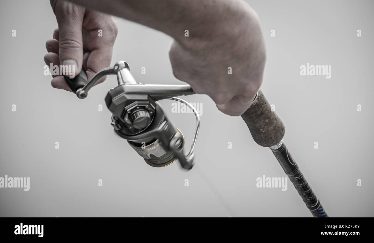 Fishing rod, man spinning the wheel Stock Photo - Alamy