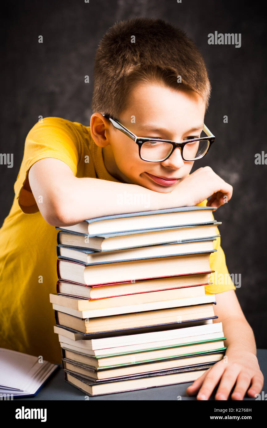 Boy taking a rest on top of piled books Stock Photo - Alamy