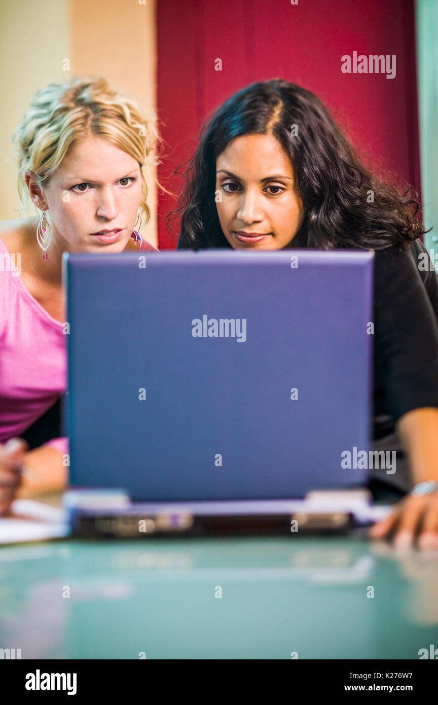 Two young business professionals working together with a laptop ...