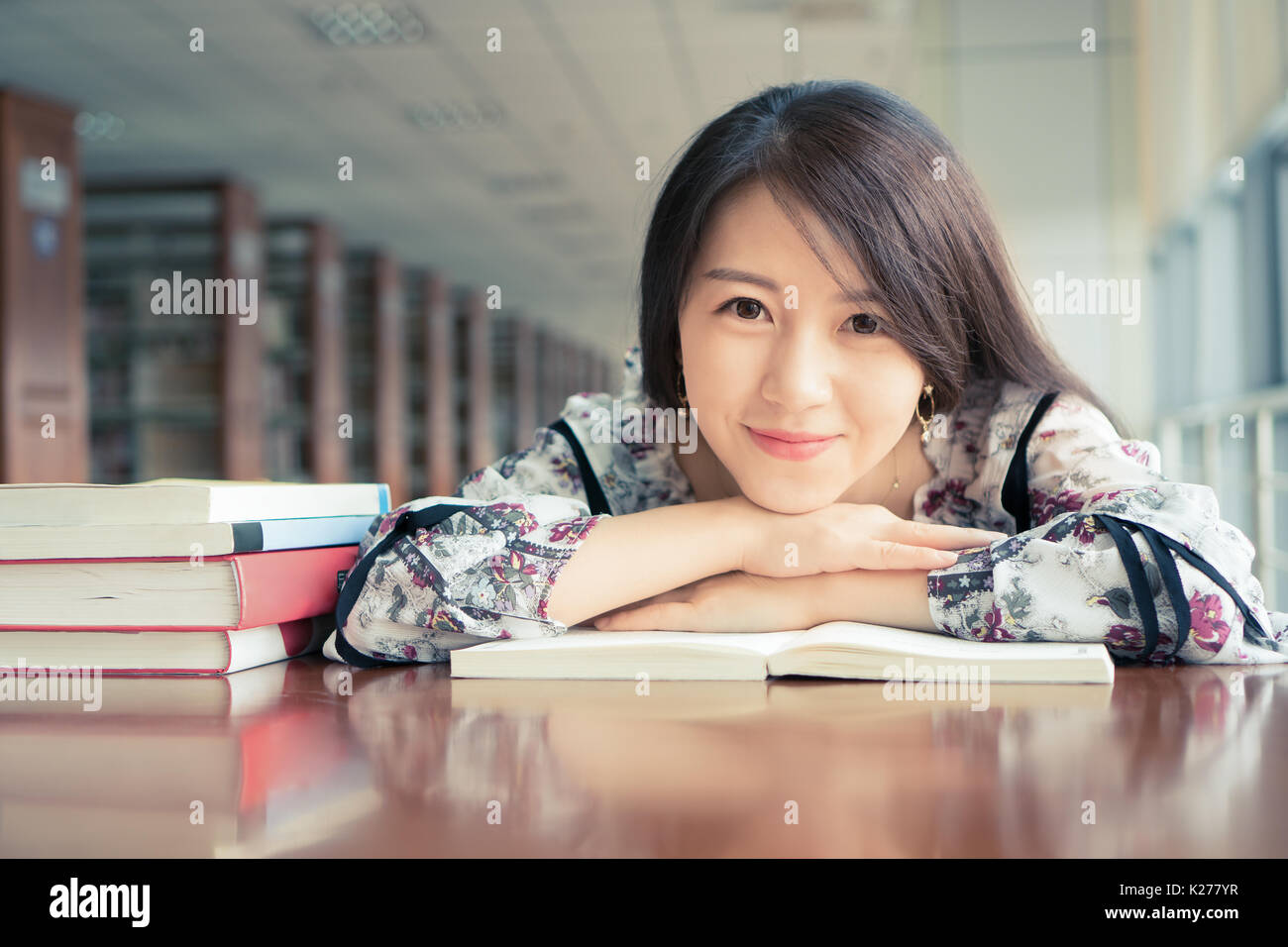 Pretty girl on the book in the library Stock Photo - Alamy
