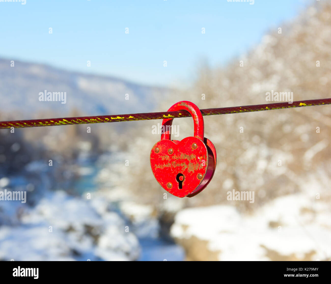 old closed red padlock in heart shape on a background of a winter ...