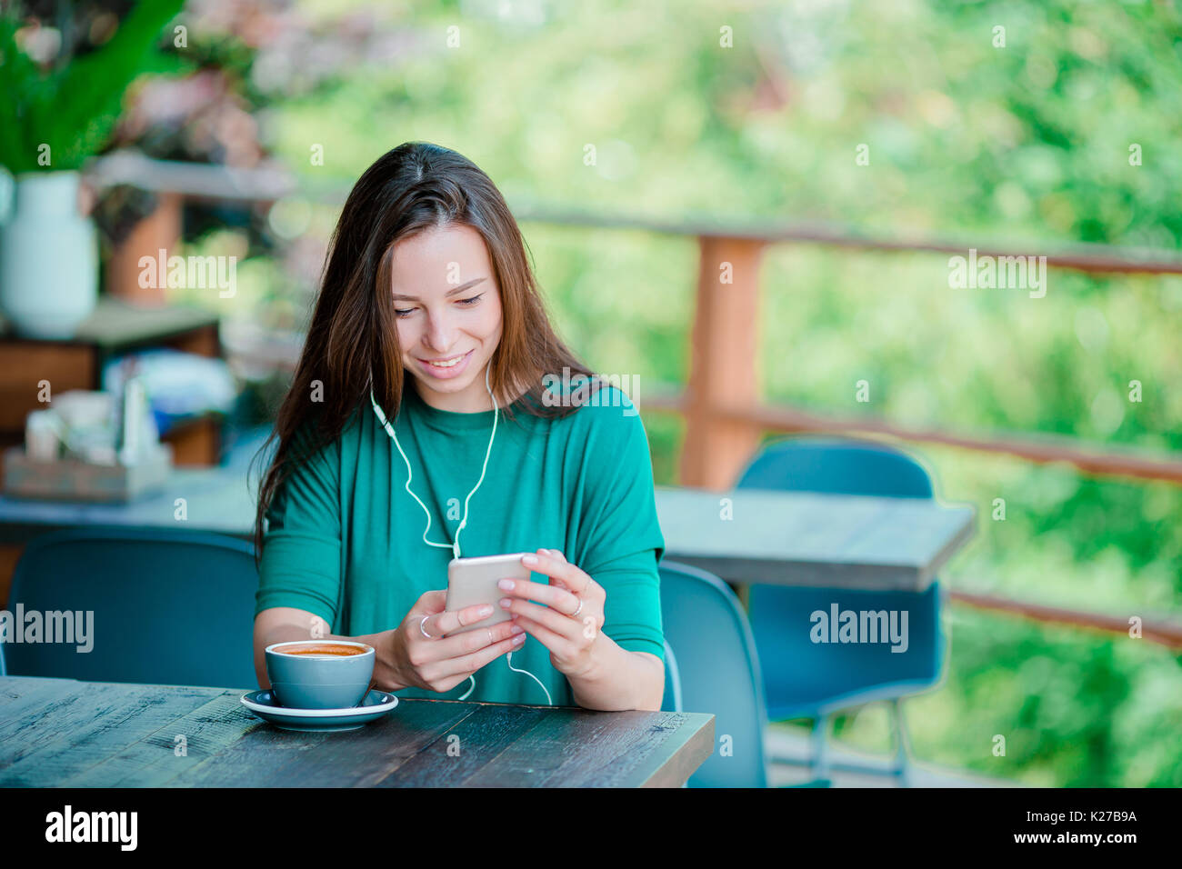 Young charming woman calling with cell telephone while sitting alone in ...