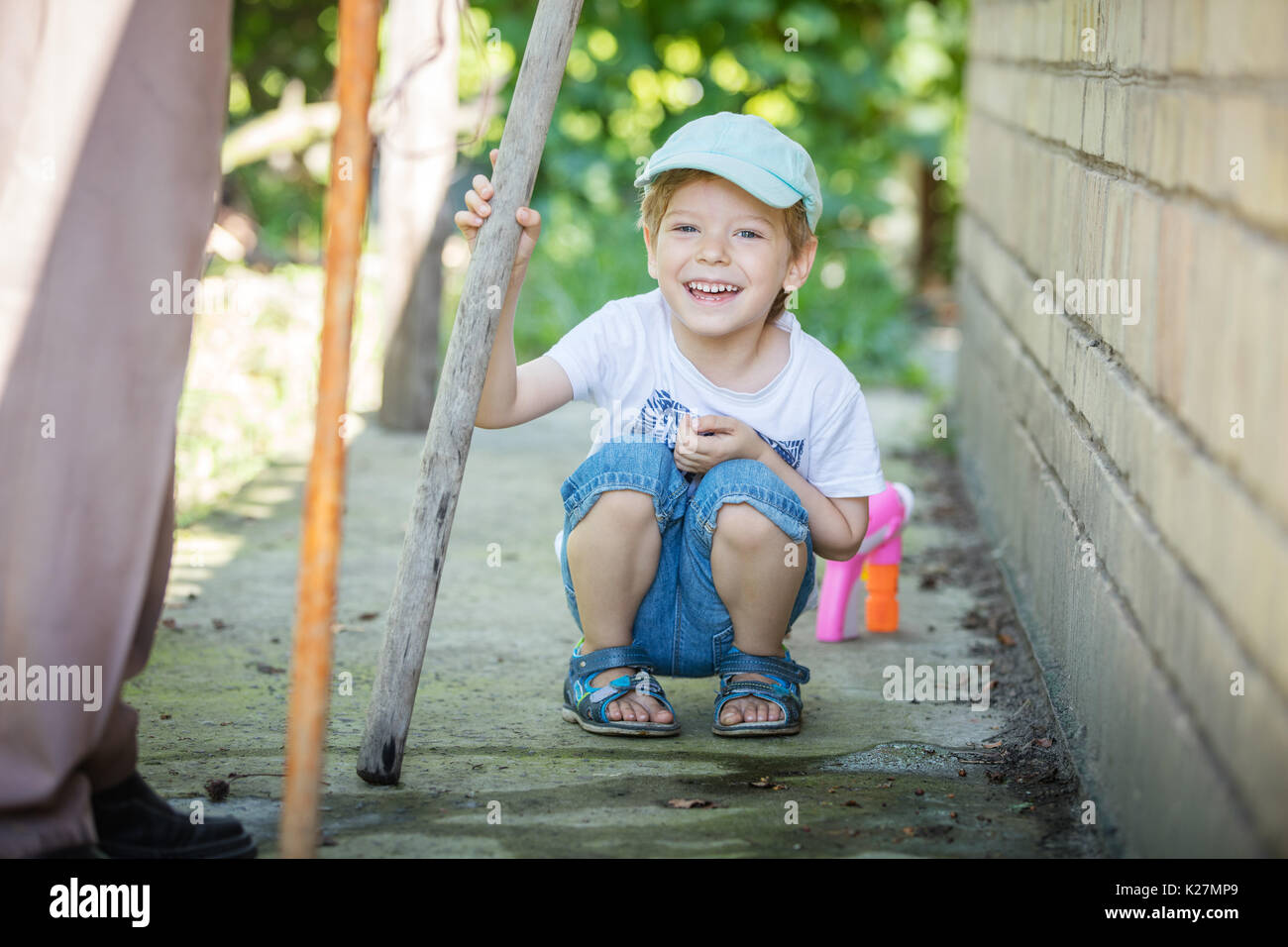 Cute little boy playing with stick outdoors, grandfather standing ...