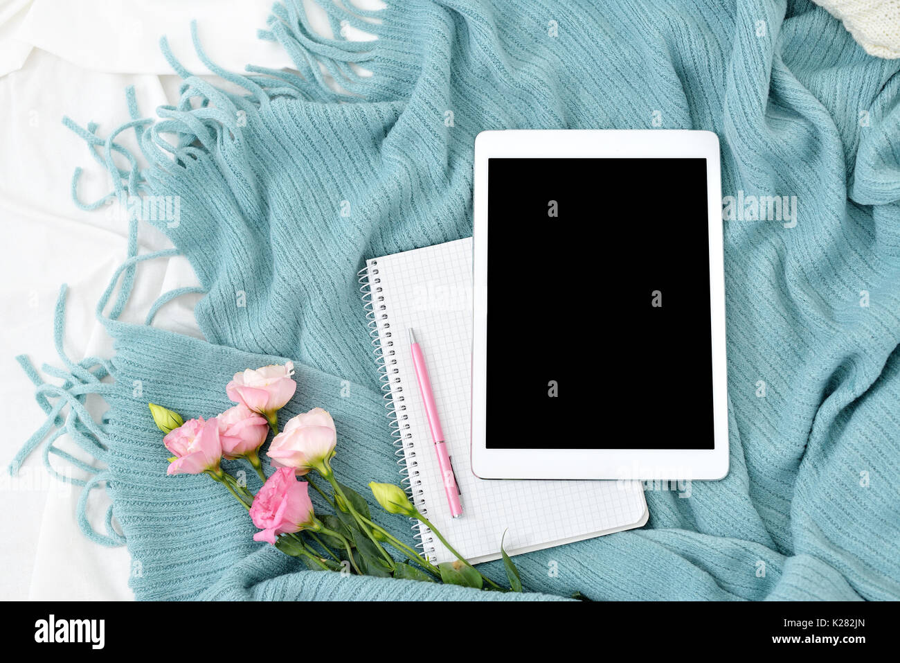 Flat lay tablet and flowers on white blanket with turquoise plaid ...