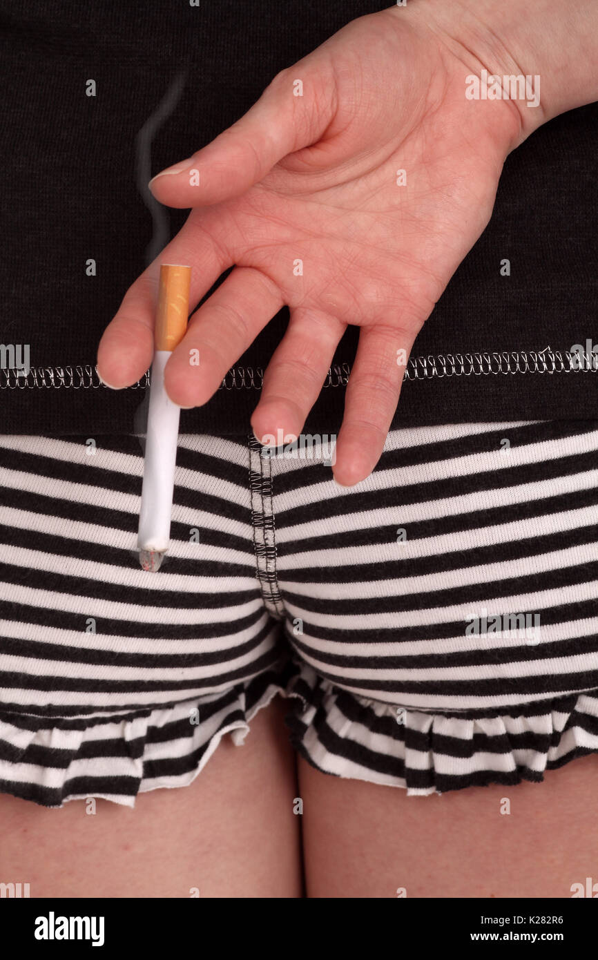 Young woman holding a cigarette behind her back Stock Photo - Alamy
