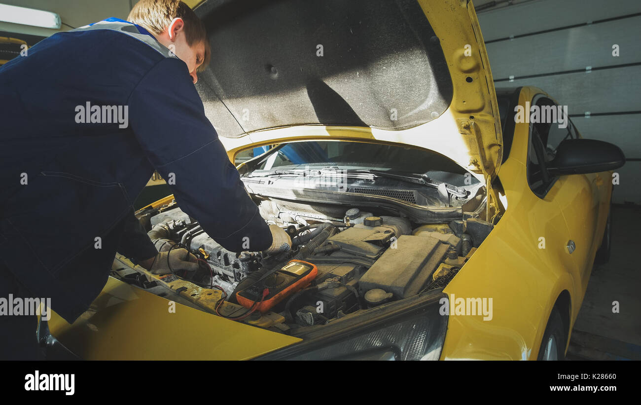 Mechanic caucasian in car service - repairing in engine compartment ...