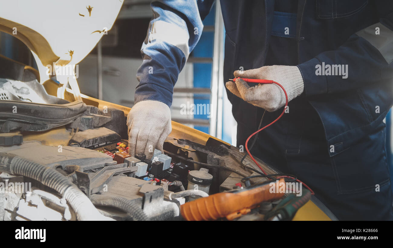 Mechanic works car electrics with voltmeter - electrical wiring Stock ...