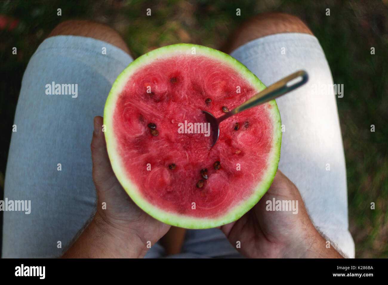 A young man is eating a watermelon with a spoon. The concept of healthy ...