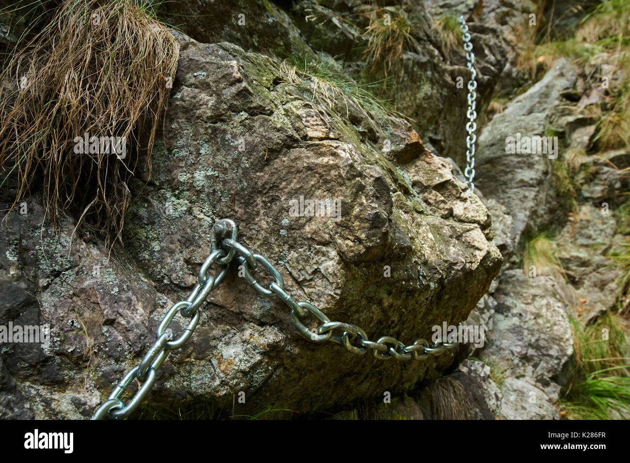 Safety chain hanging on boulders on a dangerous mountain trail Stock ...