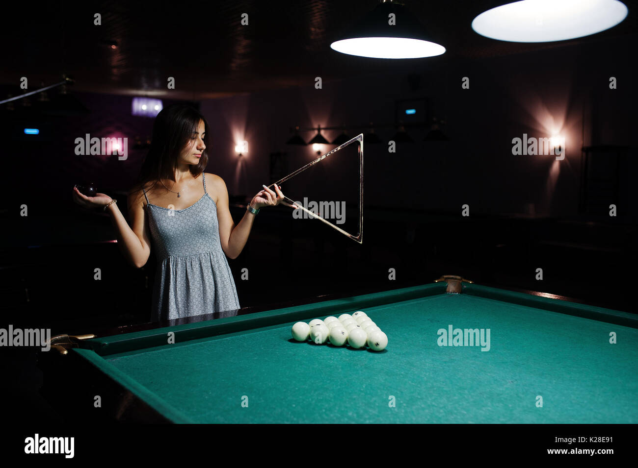 Portrait of a confused woman posing with a triangle by the pool table ...