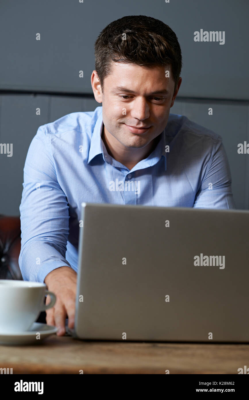 Businessman Working On Laptop In Internet Cafe Stock Photo - Alamy
