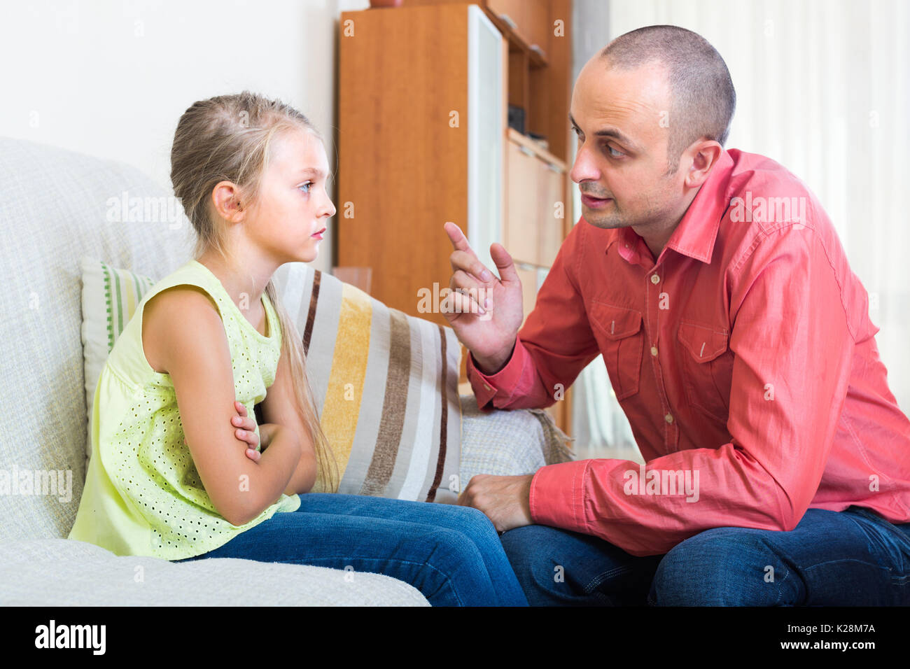 Father lecturing unpleased little girl in home interior Stock Photo - Alamy