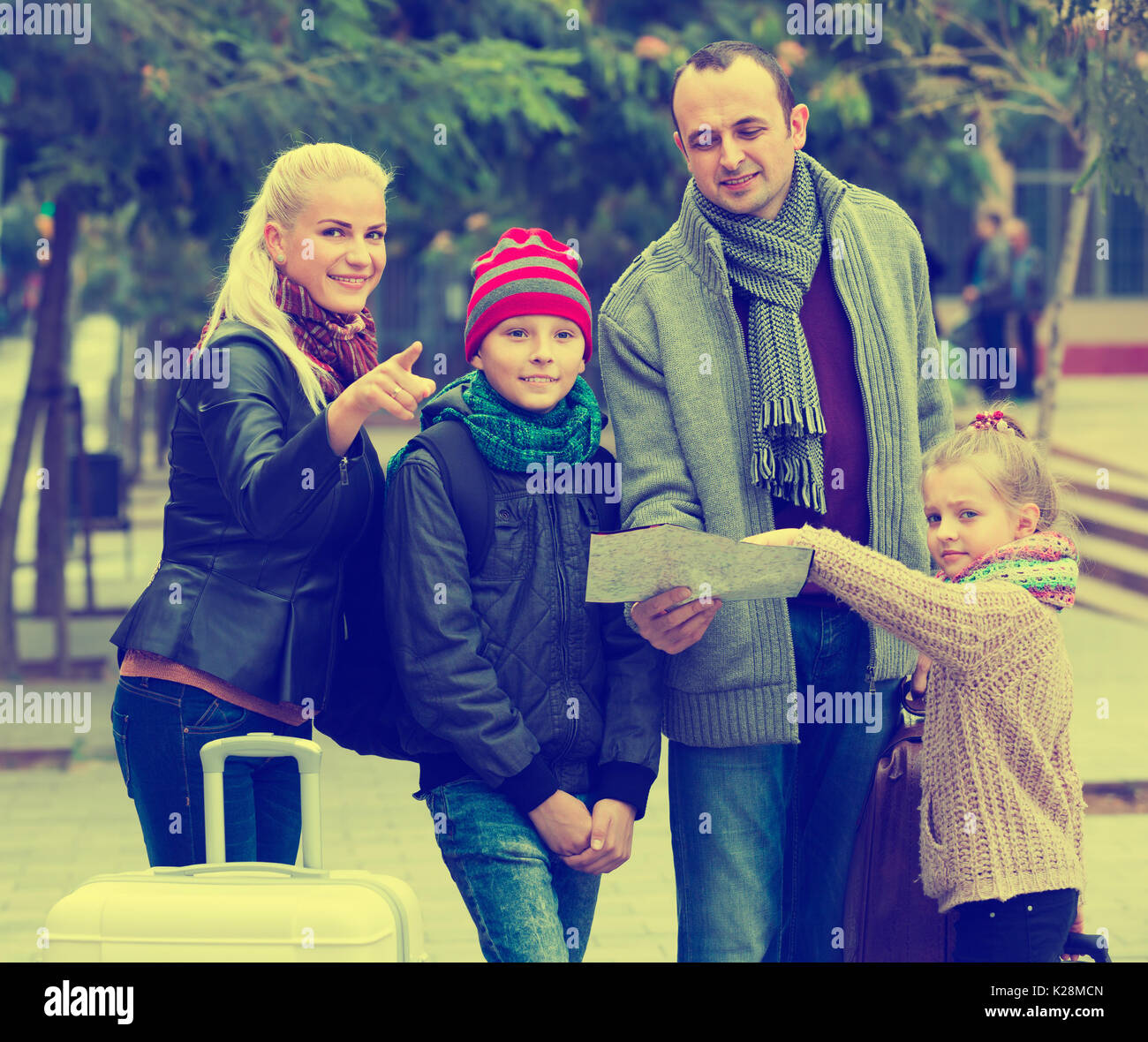 Happy middle class family of four checking direction in the city map ...