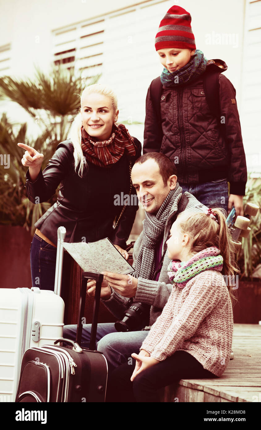 Happy middle class family of four checking direction in map outdoor ...