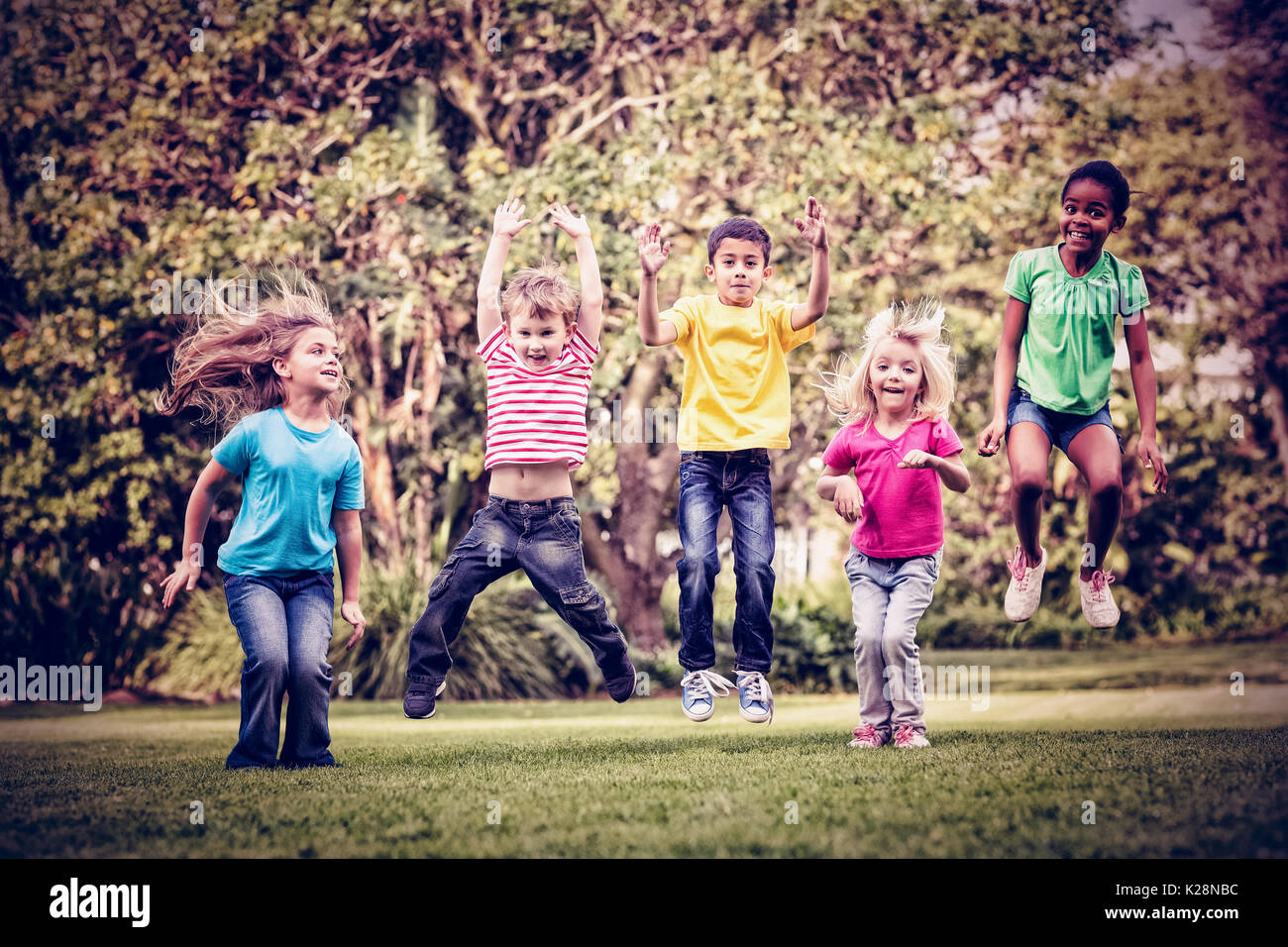 Happy children jumping at park Stock Photo - Alamy