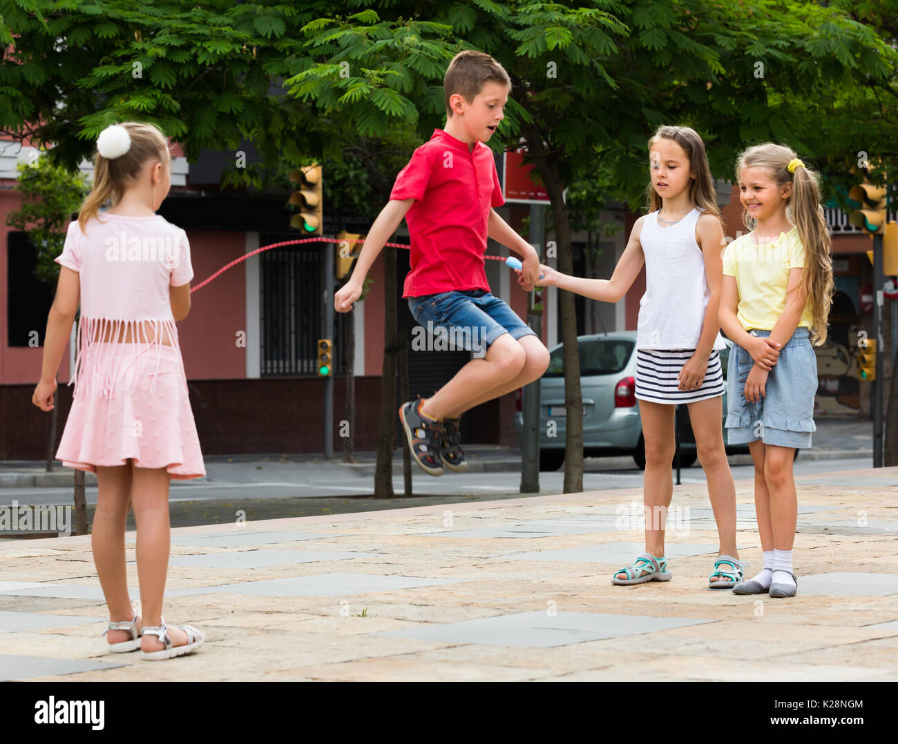 group of smiling children skipping together with jumping rope on urban ...