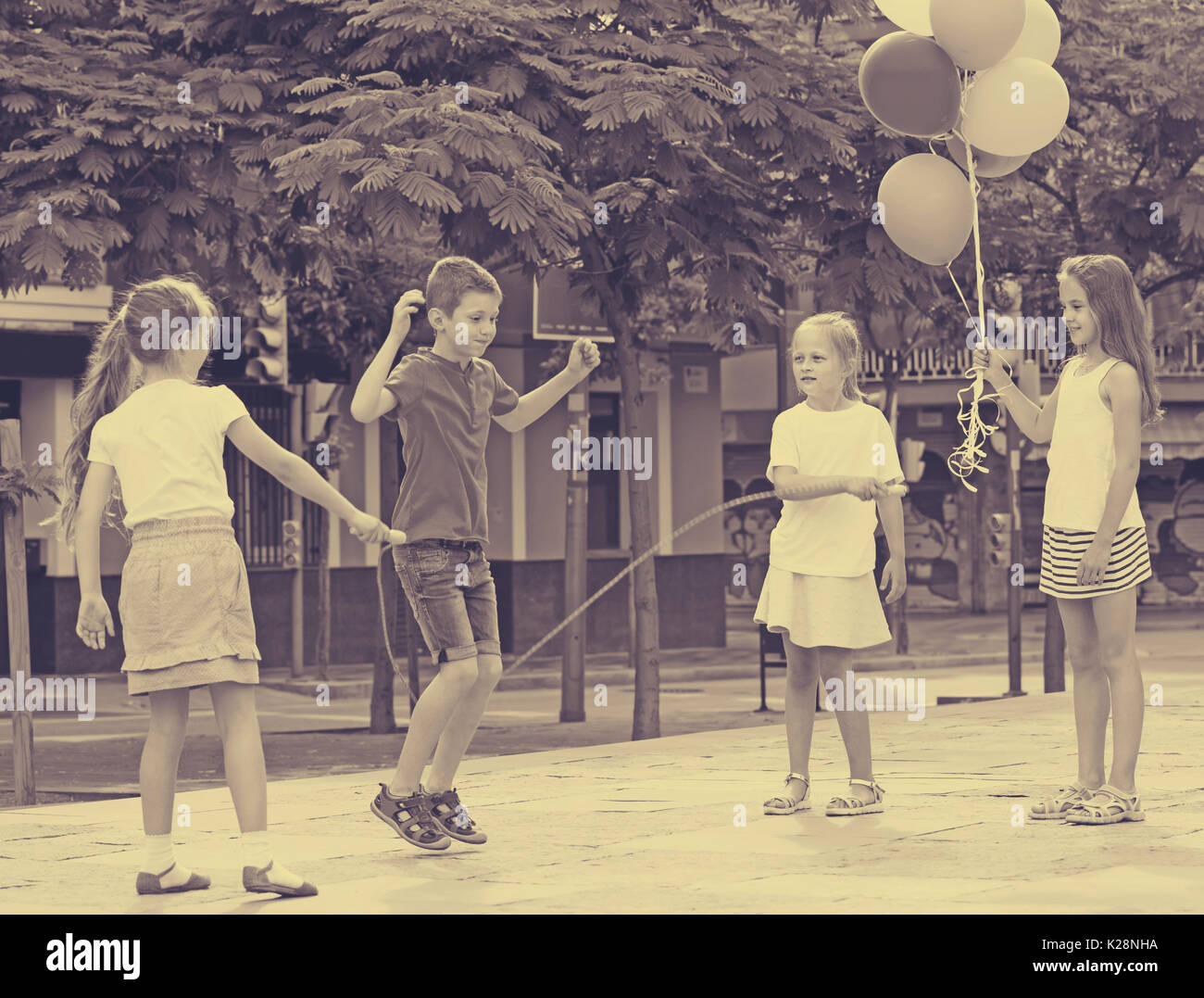 group of happy children skipping together with jumping rope on urban ...