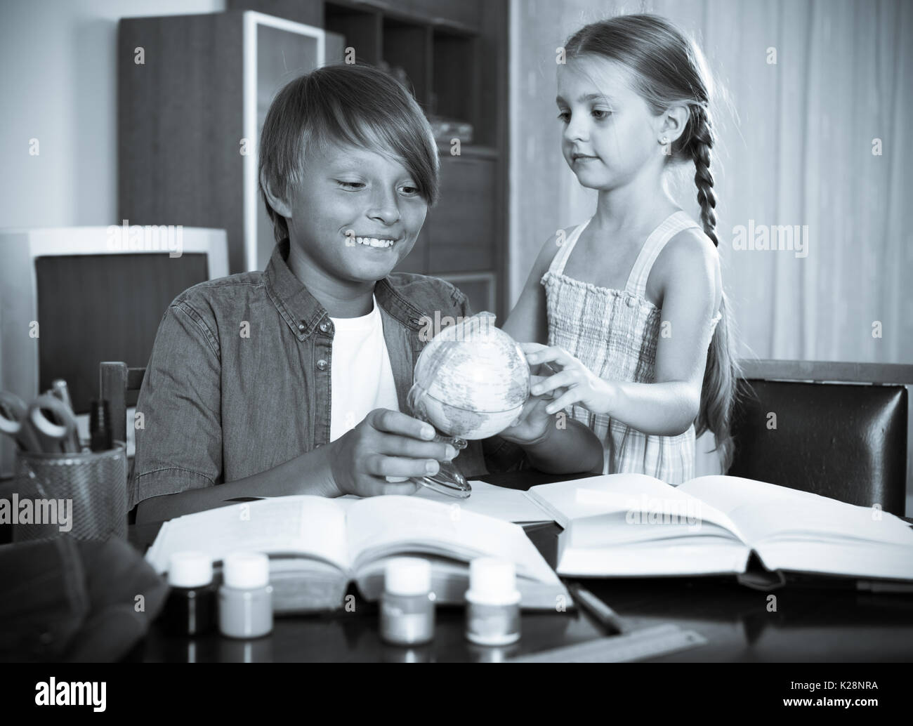 Happy big brother helping little girl to do homework at home. Focus on ...