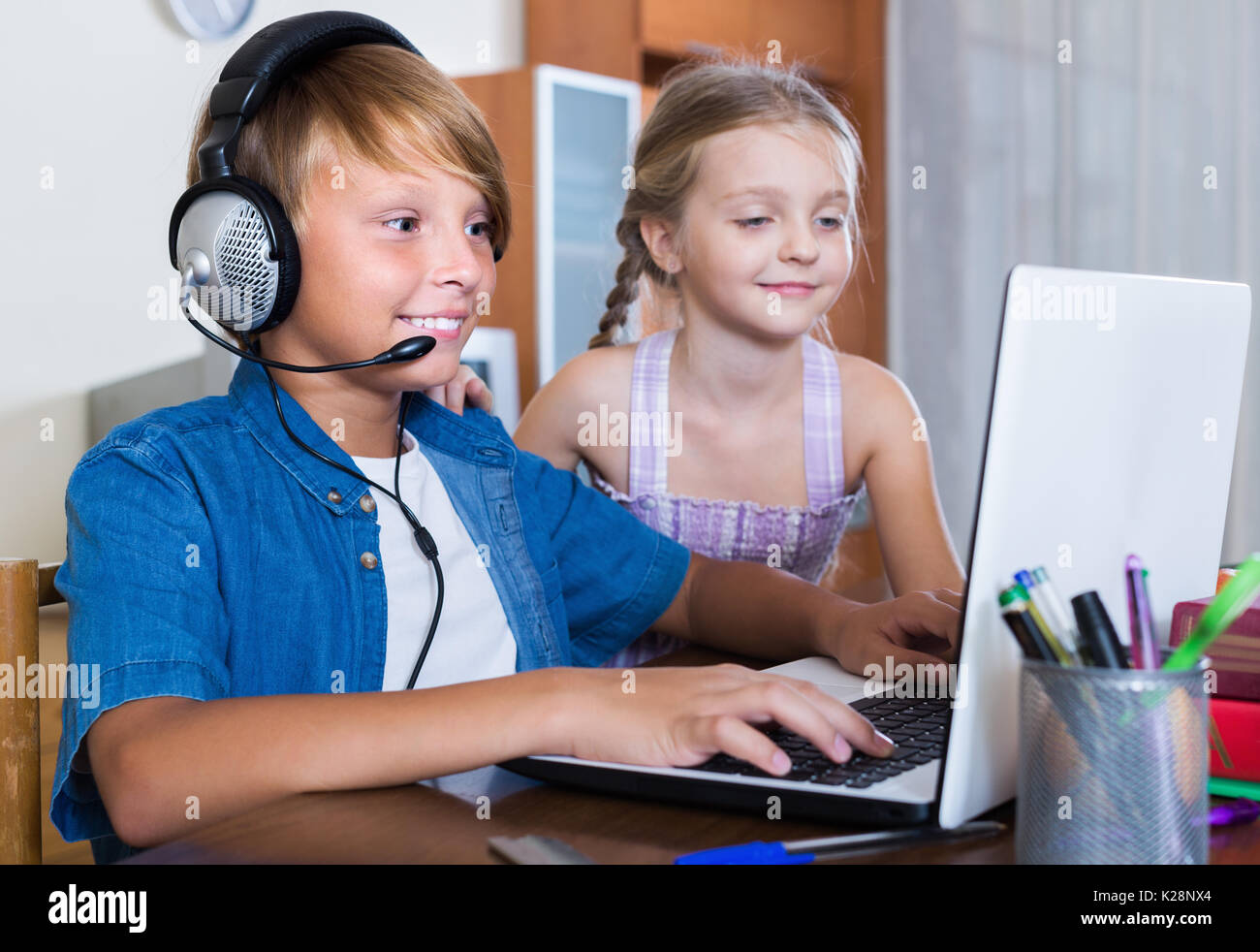 Teenager and his little sister playing game on laptop Stock Photo - Alamy