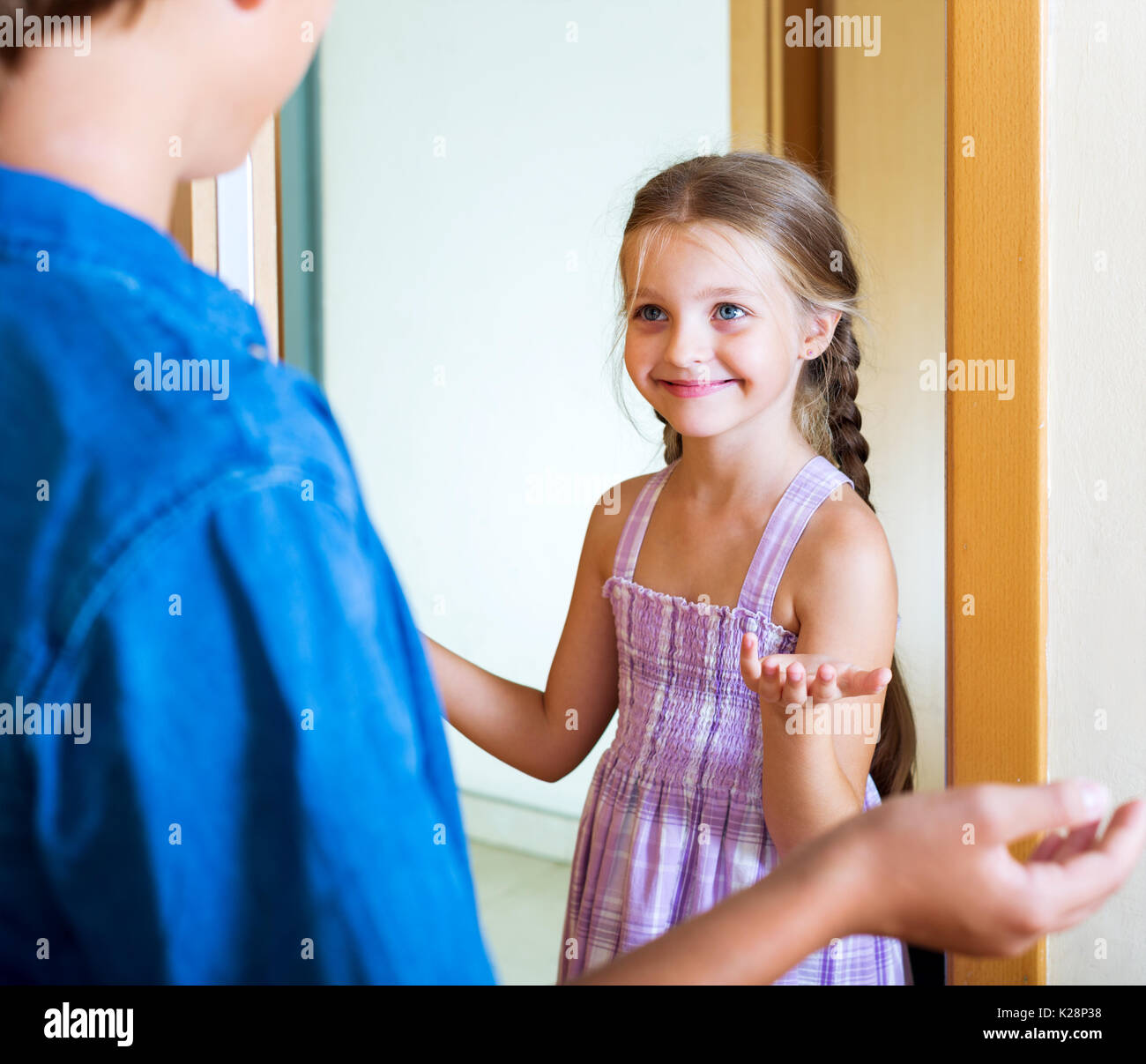 Happy kid welcoming friend in doorway and smiling Stock Photo - Alamy