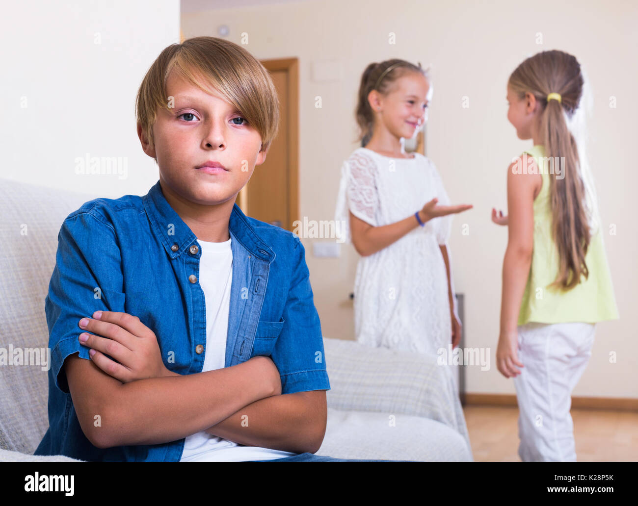 Two little spanish girls talking and sulky boy sitting separately at ...
