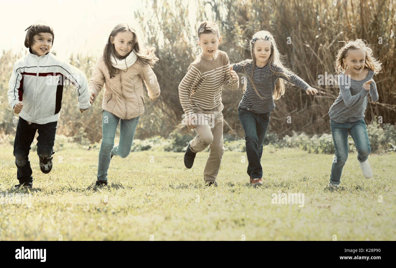 Excited kids full of energy run in race through field Stock Photo - Alamy