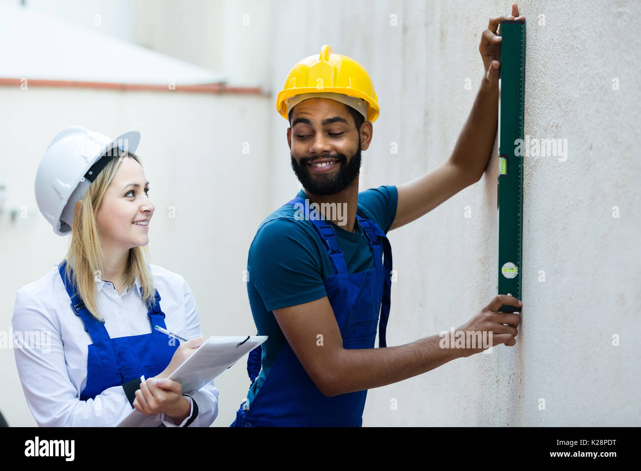 Constructor and smiling spanish professional builder with spirit level ...