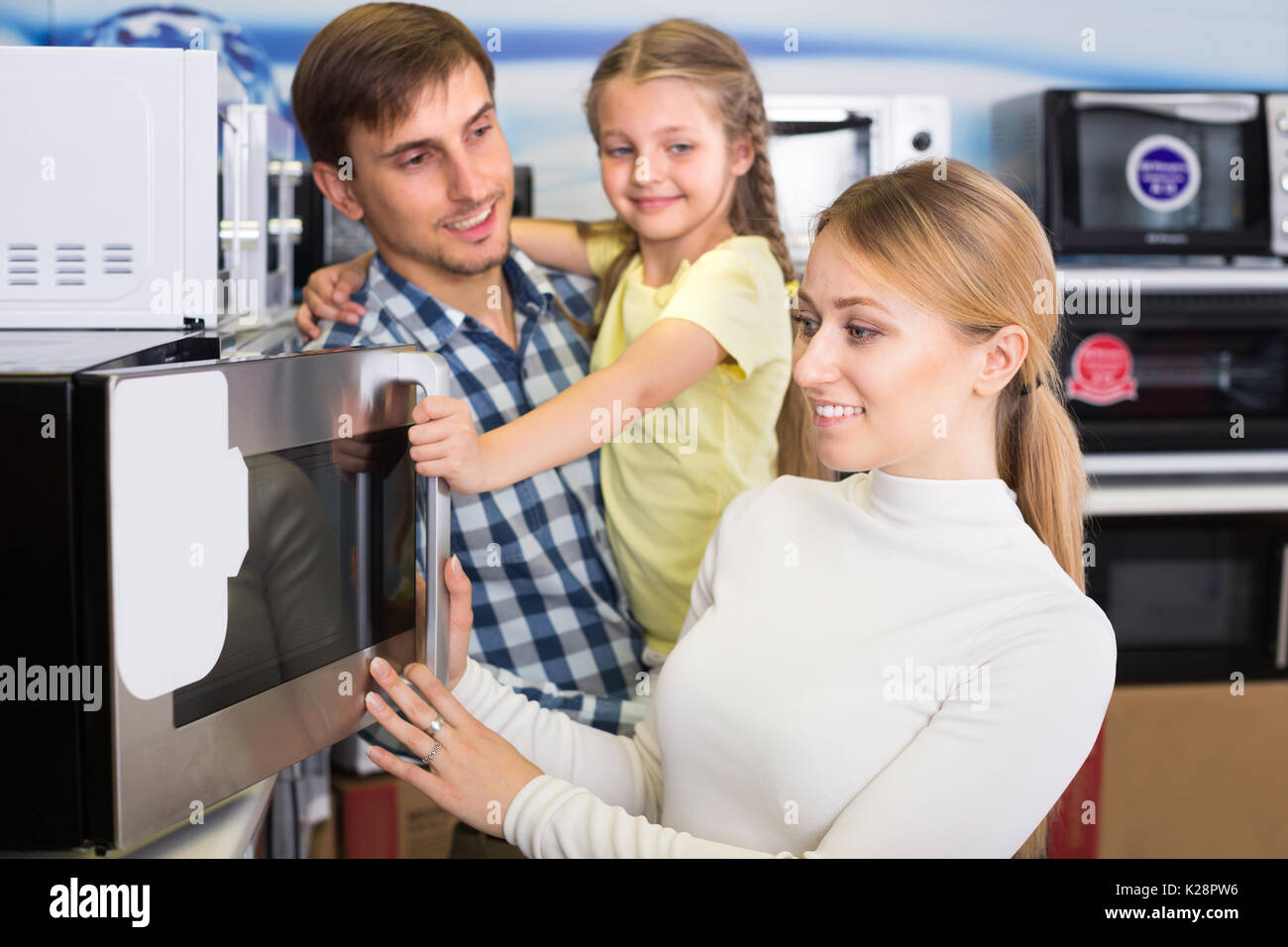 Portrait of smiling family selecting microwave oven in hypermarket ...