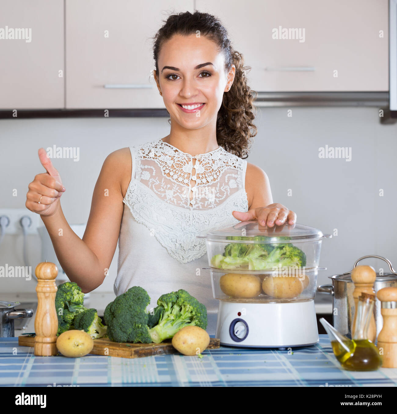 Happy cheerful housewife on diet cooking vegetables in a steamer ...
