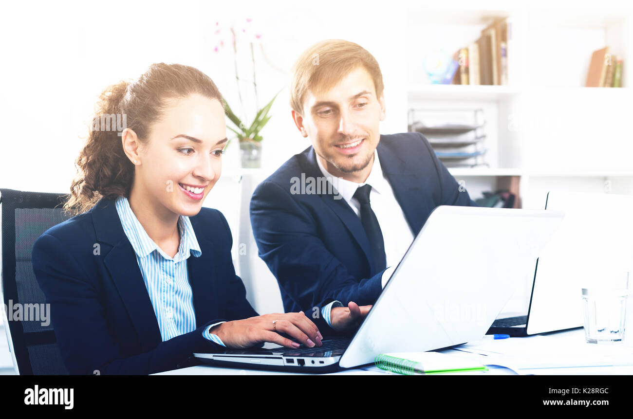 Man and positive woman coworkers sitting and working on computers in ...