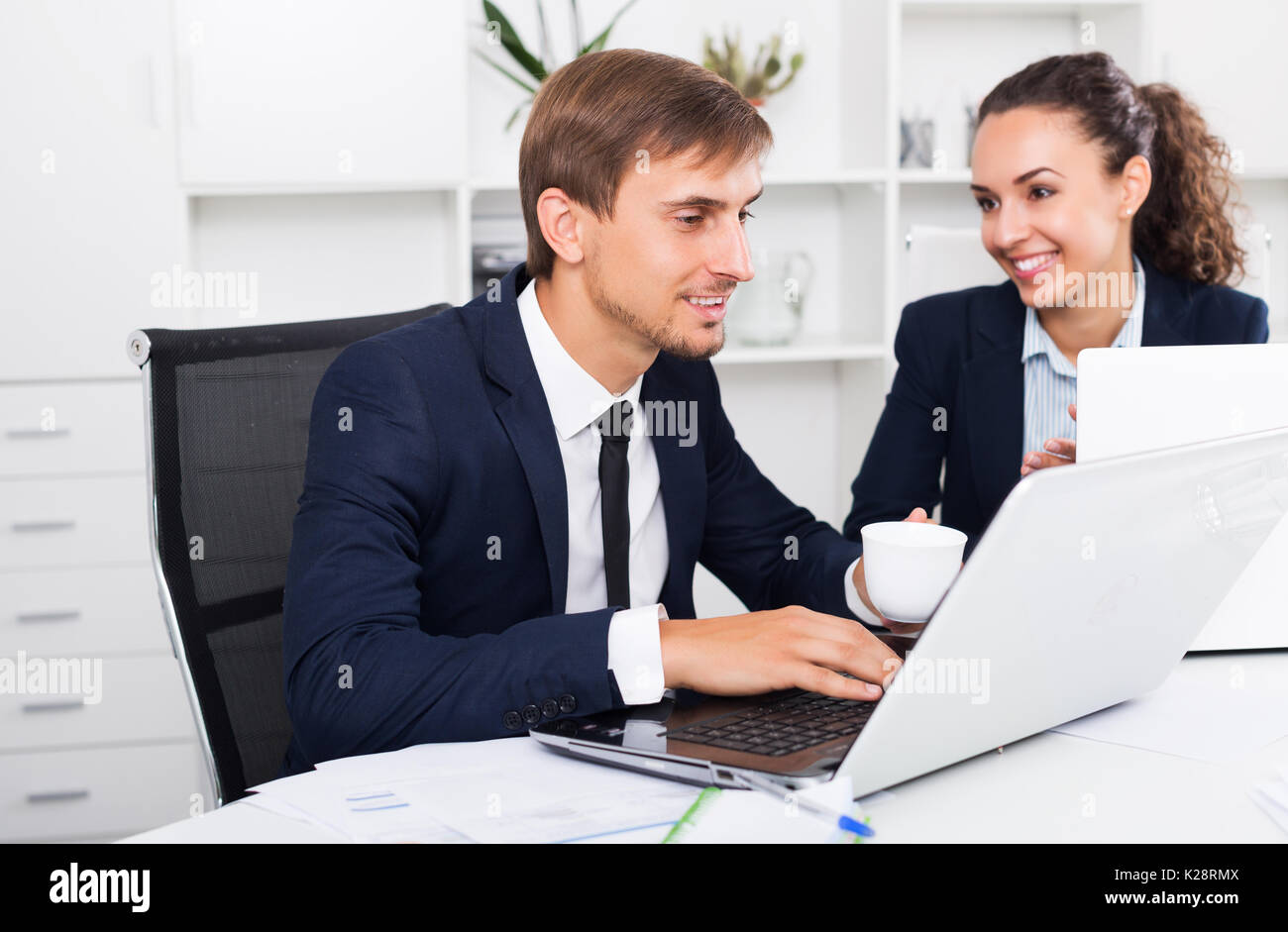 Portrait of positive business man and woman colleagues sitting with ...