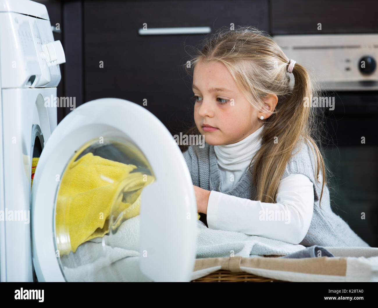 Happy little girl doing laundry in home interior Stock Photo - Alamy