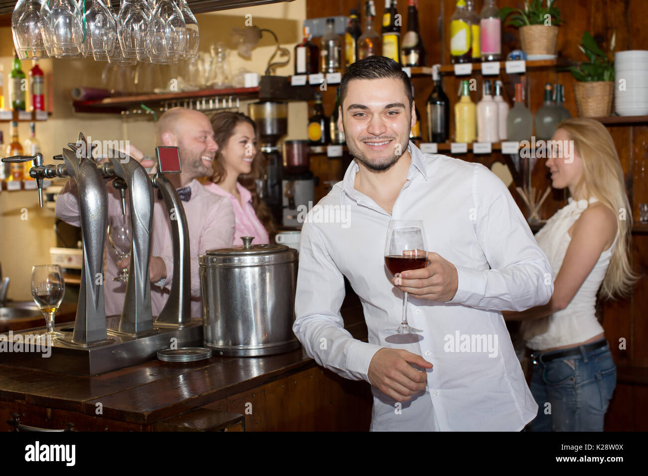 Positive bartender entertaining guests at the bar counter Stock Photo ...