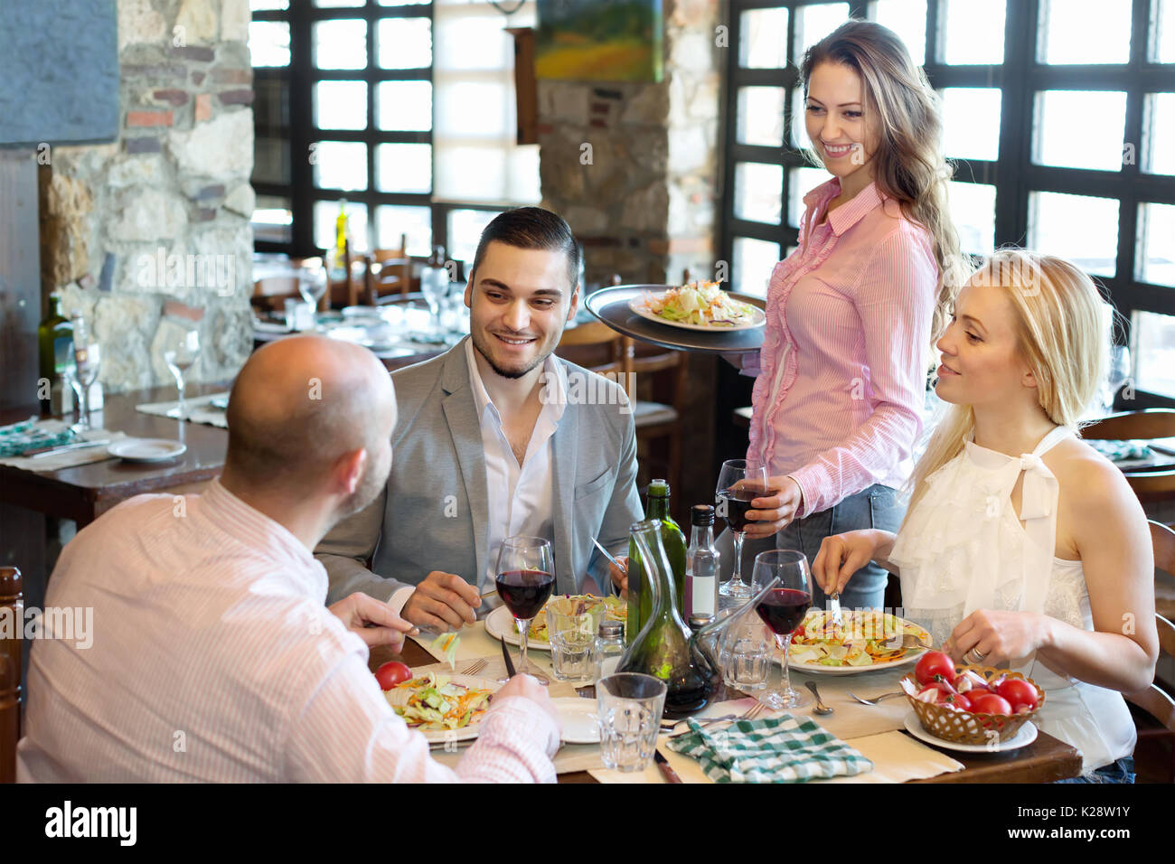 Portrait of happy people having dinner and respectful waiter Stock ...