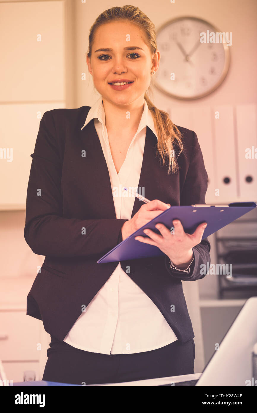 Female assistant standing in office and noting tasks Stock Photo - Alamy