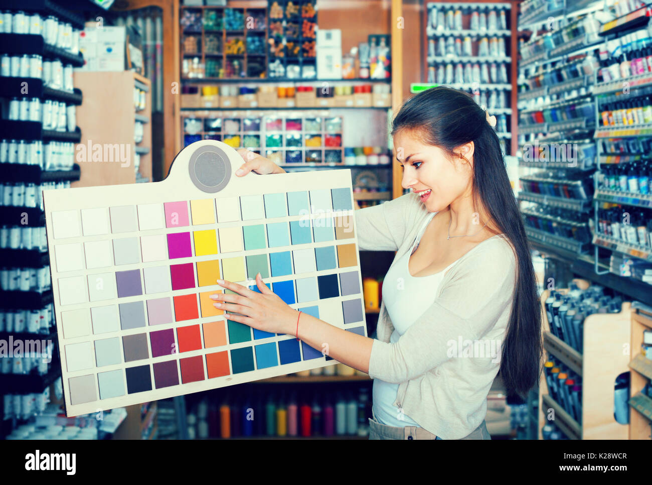Young smiling woman choosing paint color using sample palette in art ...