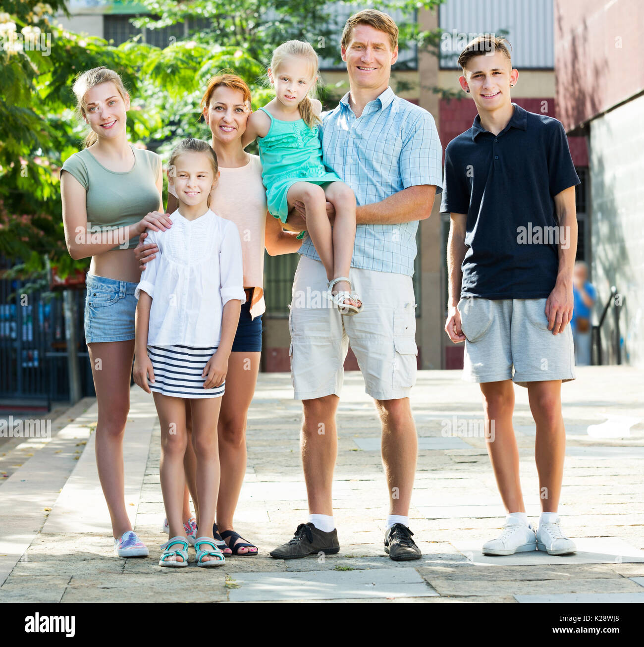Positive parents with four children in different ages taking promenade ...
